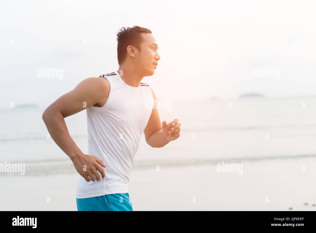 asian sport man running along seaside. running on beach with healthy ...