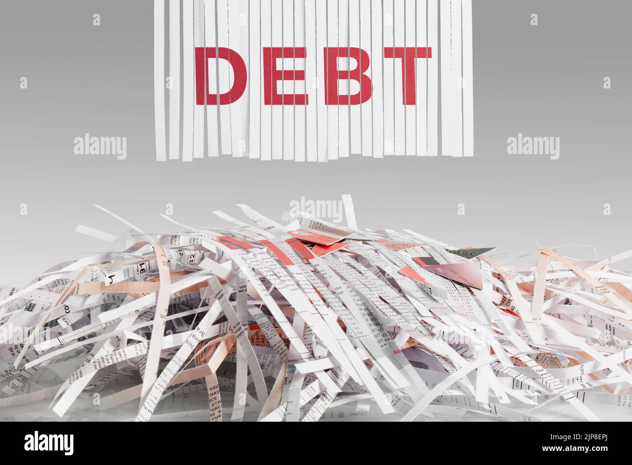 Shredded red DEBT letters above Cut up credit cards on Shredded Bills ...