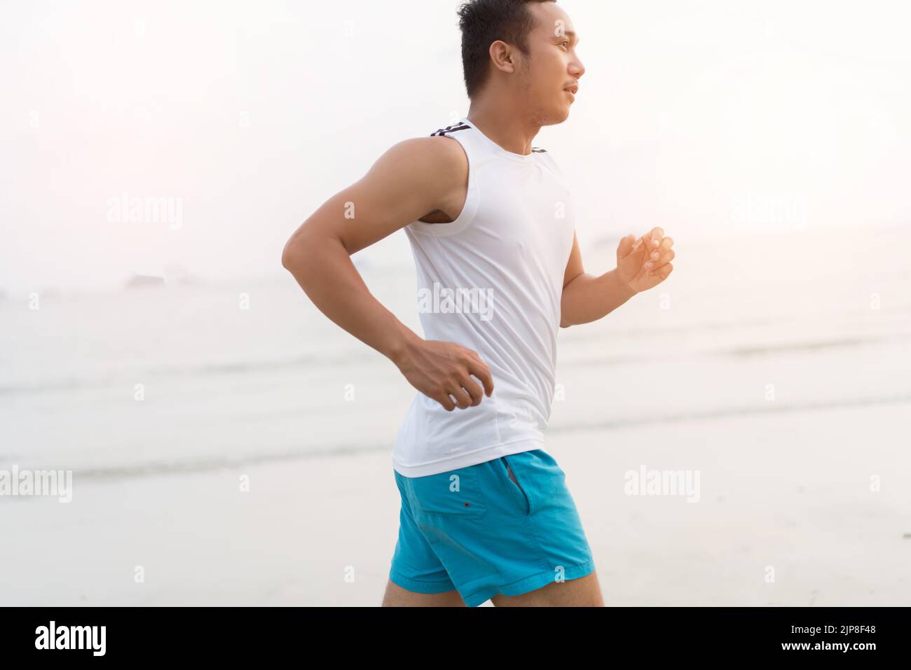 asian sport man running along seaside. running on beach with healthy ...