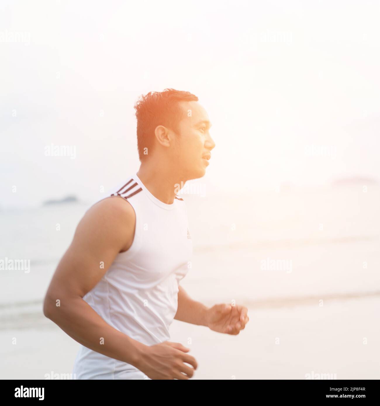 asian sport man running along seaside. running on beach with healthy ...