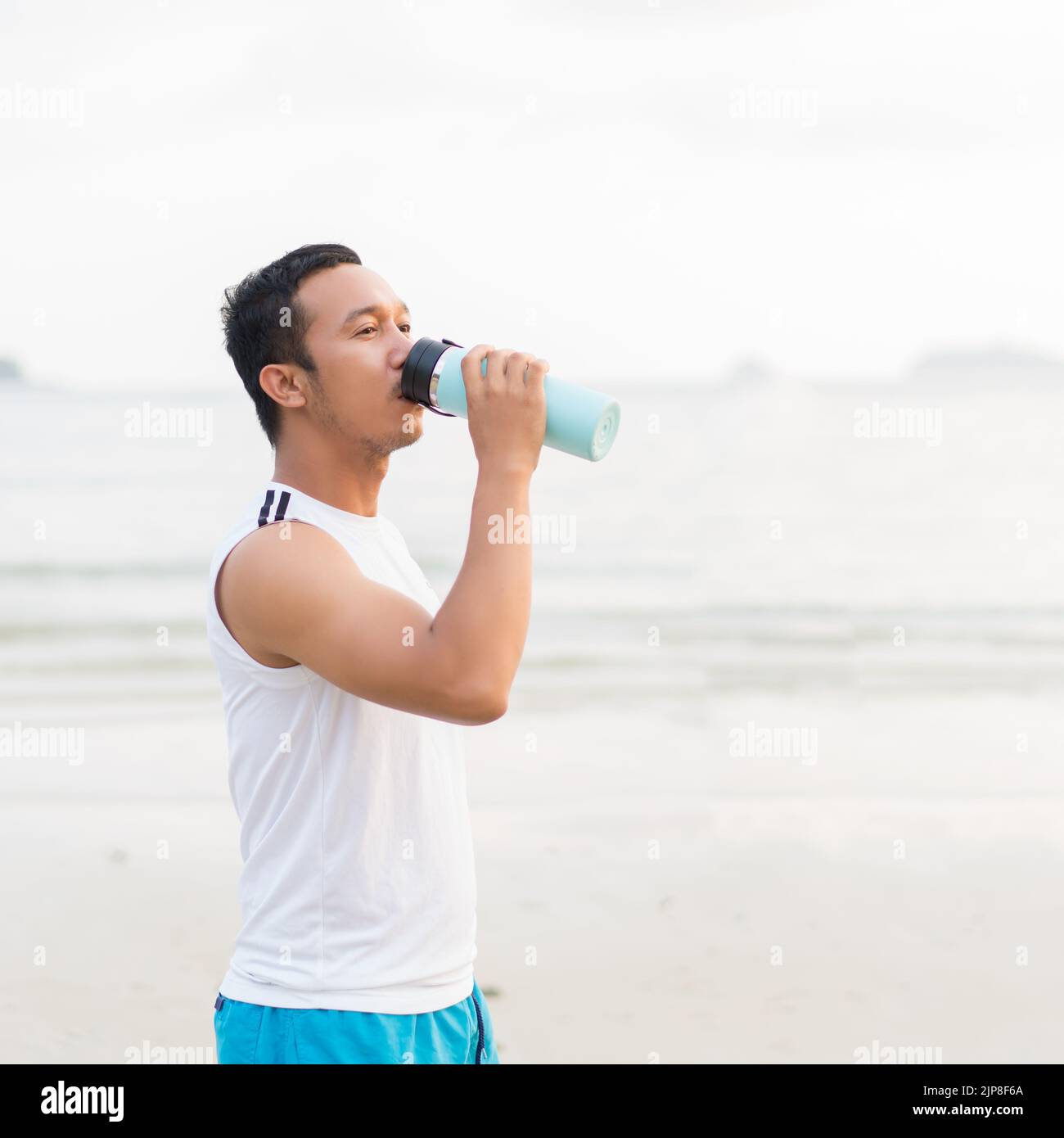 asian sport man drinking water while enjoying a morning run on the ...