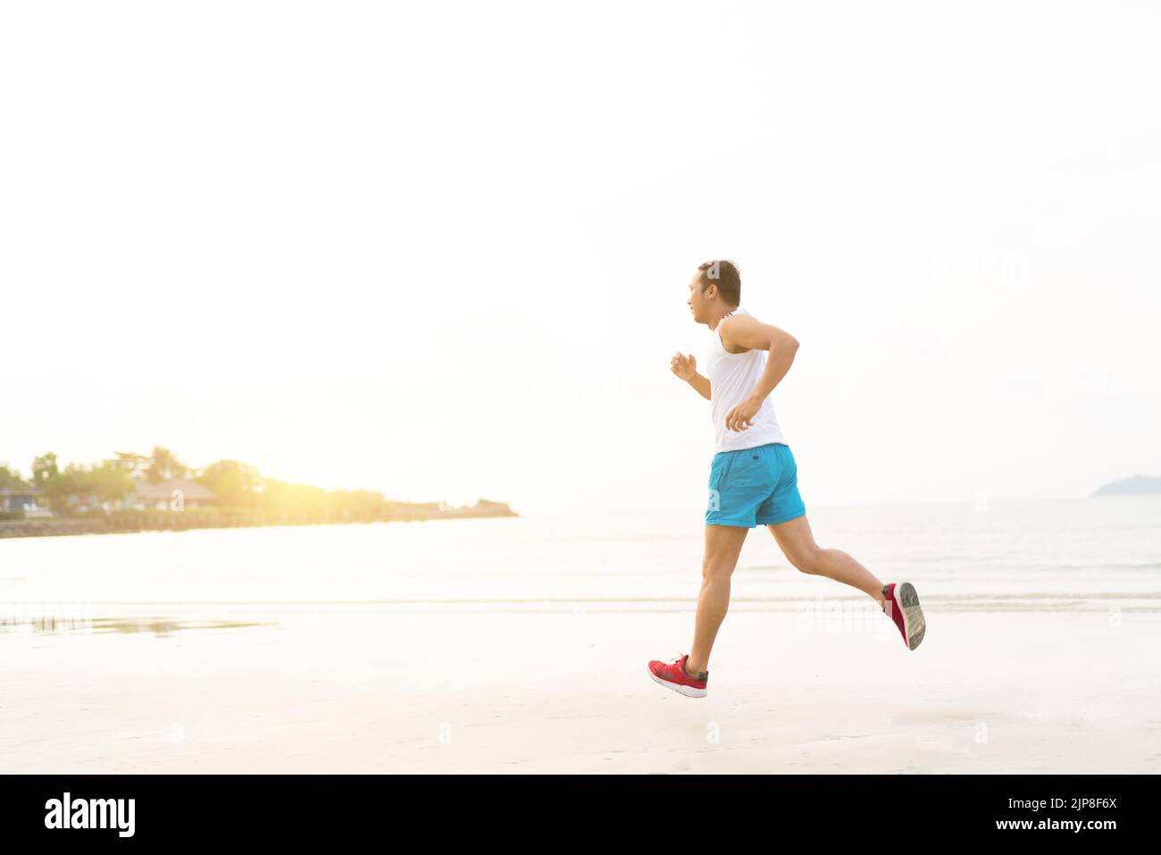 asian sport man running along seaside. running on beach with healthy ...