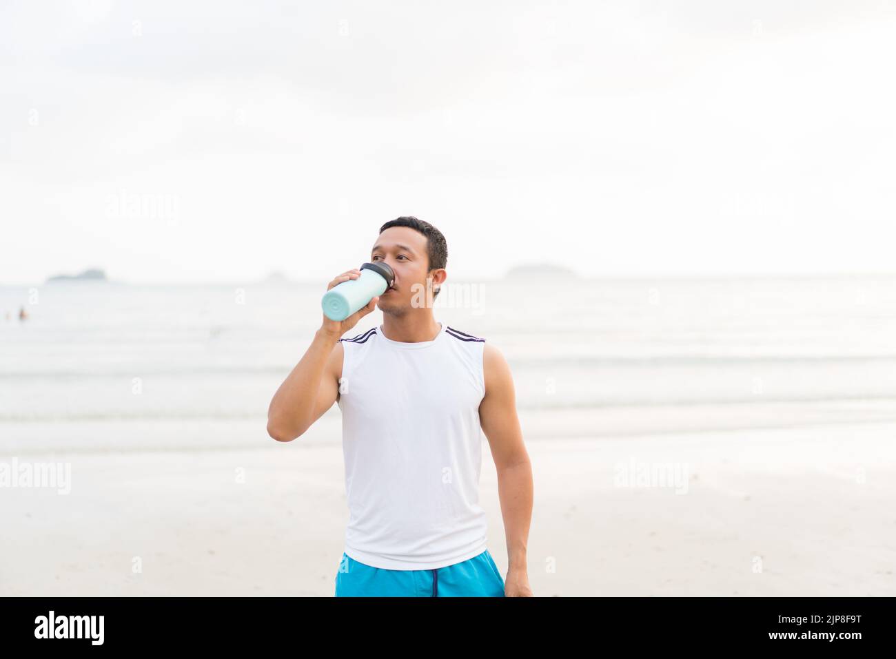 asian sport man drinking water while enjoying a morning run on the ...