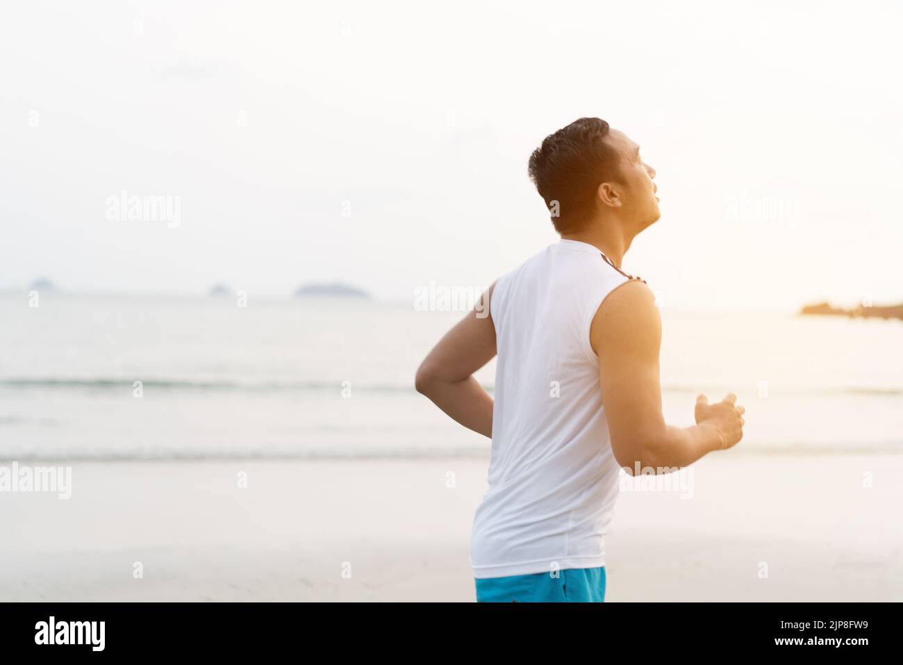 asian sport man running along seaside. running on beach with healthy ...