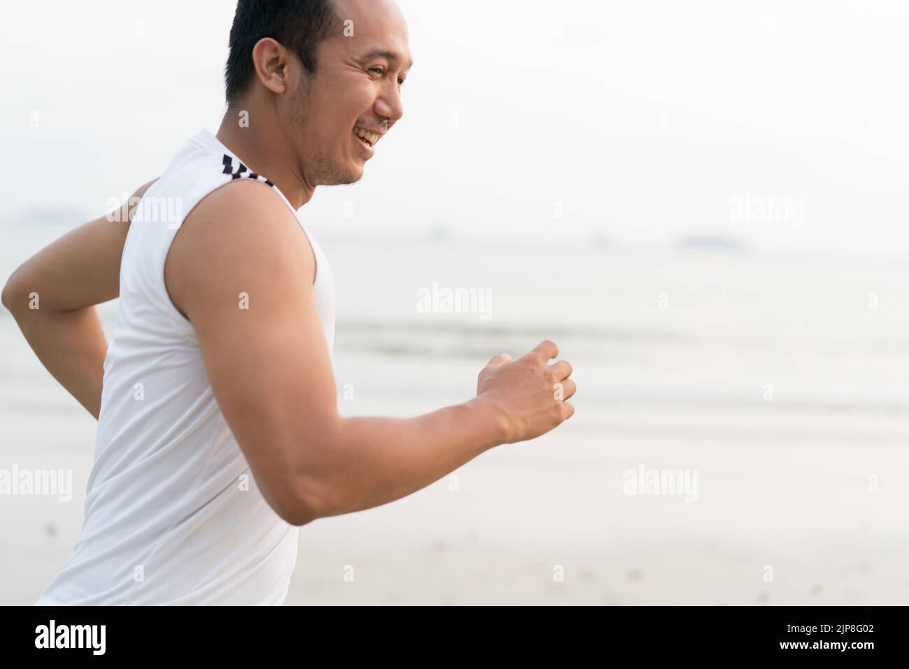 asian sport man running along seaside. running on beach with healthy ...