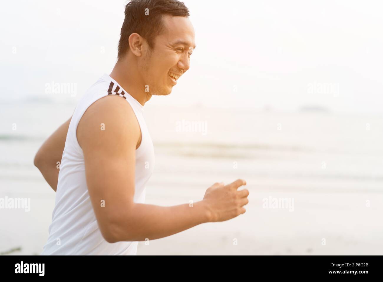 asian sport man running along seaside. running on beach with healthy ...
