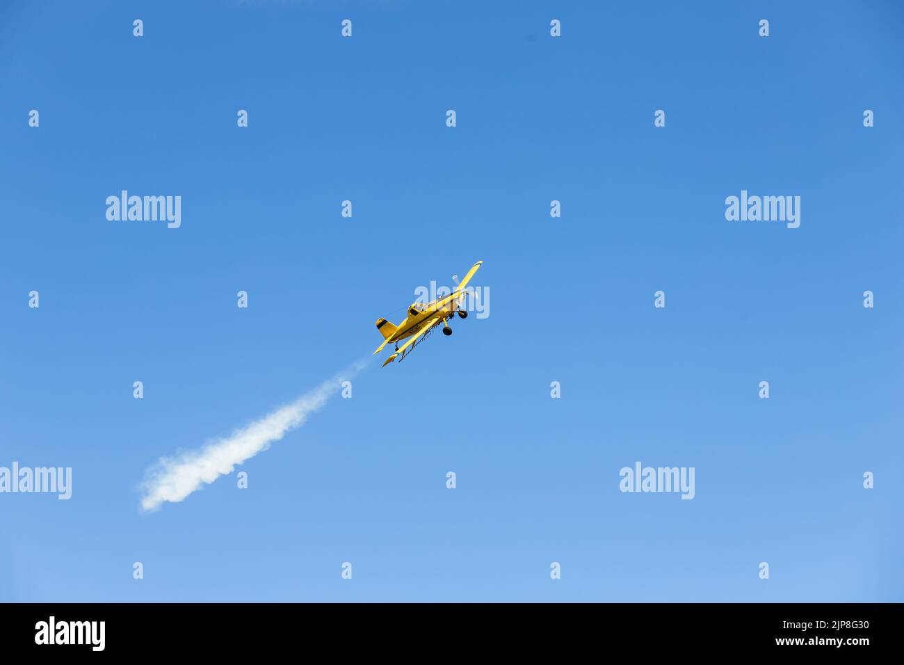 A yellow plane in flight in a blue sky Stock Photo - Alamy