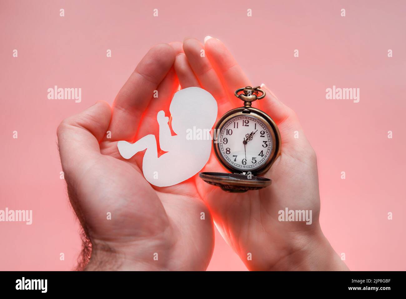 Hands of woman and man holding a silhouette of a child and clock. Paper ...