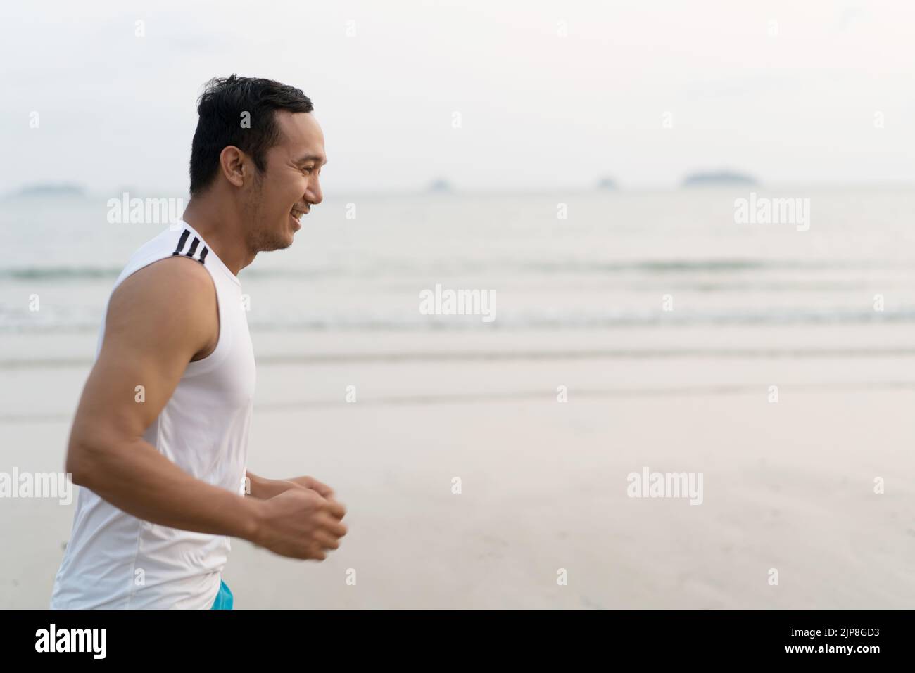 asian sport man running along seaside. running on beach with healthy ...