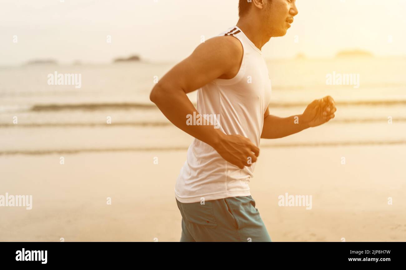 asian sport man running along seaside. running on beach with healthy ...