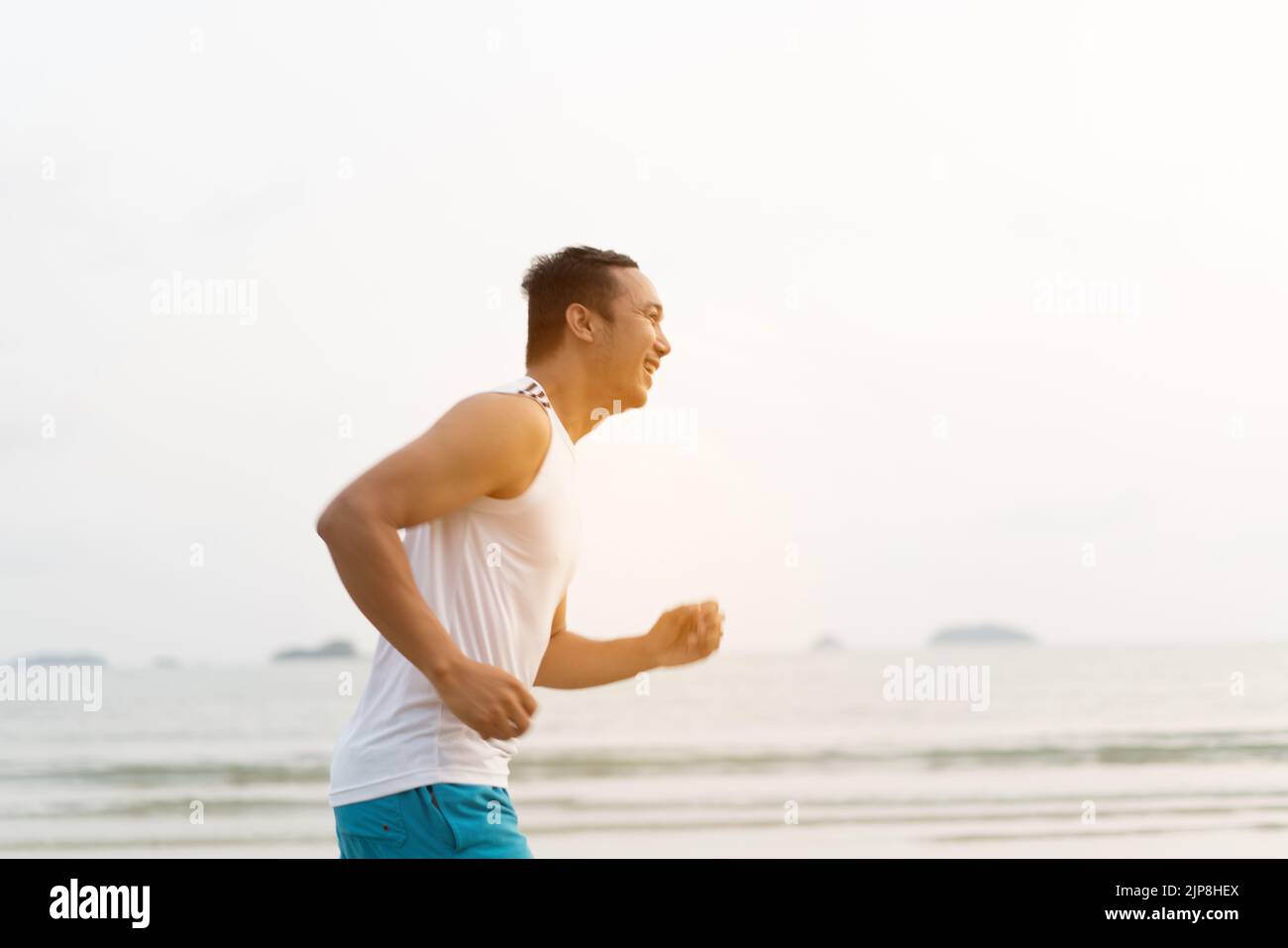 asian sport man running along seaside. running on beach with healthy ...