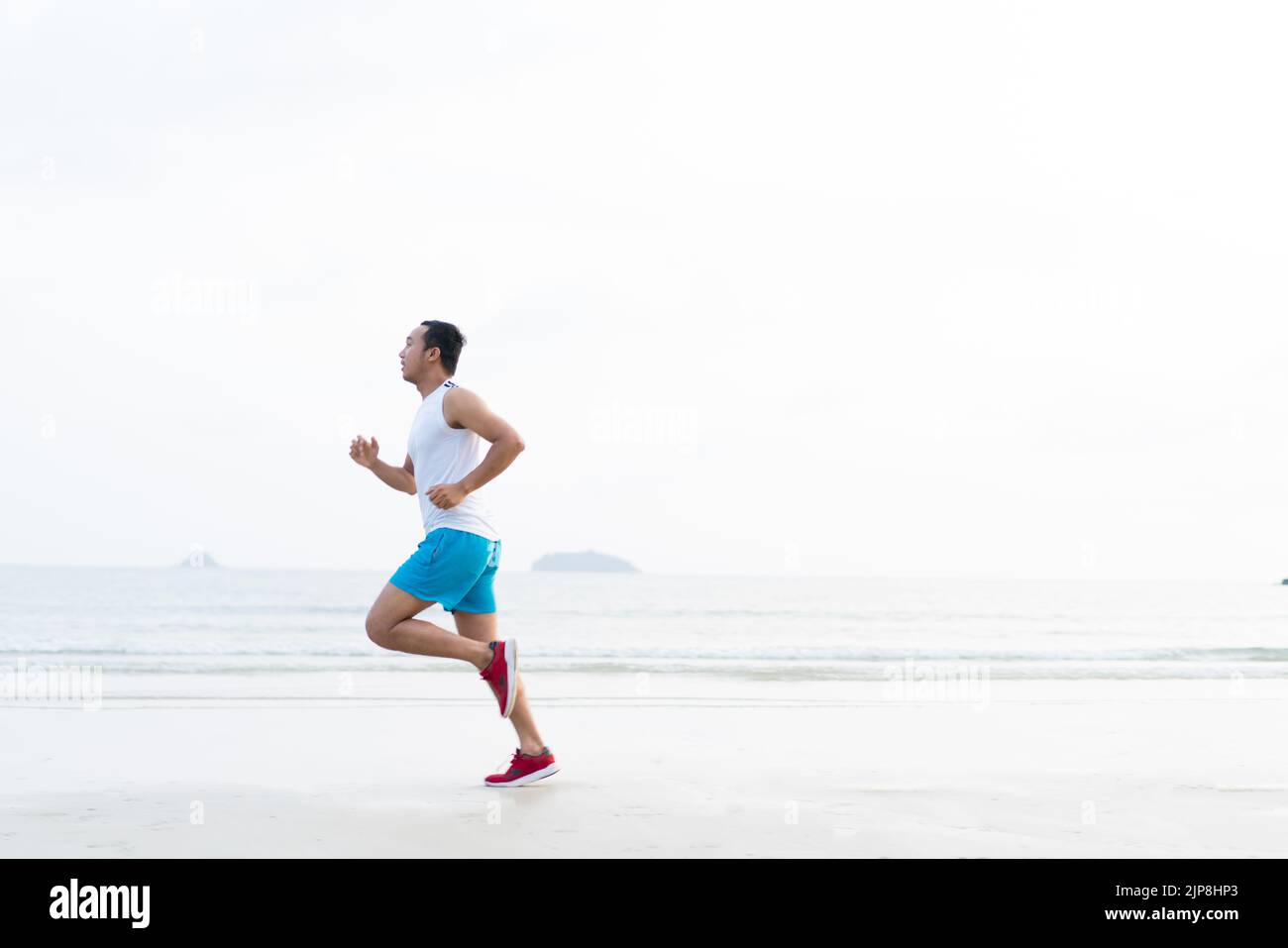 asian sport man running along seaside. running on beach with healthy ...