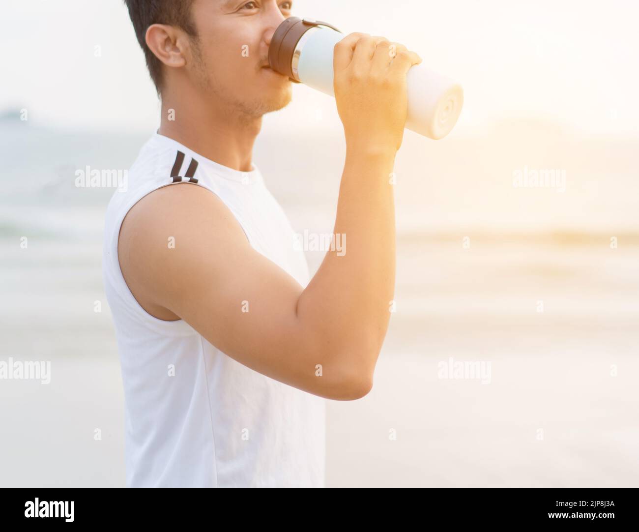 asian sport man drinking water while enjoying a morning run on the ...