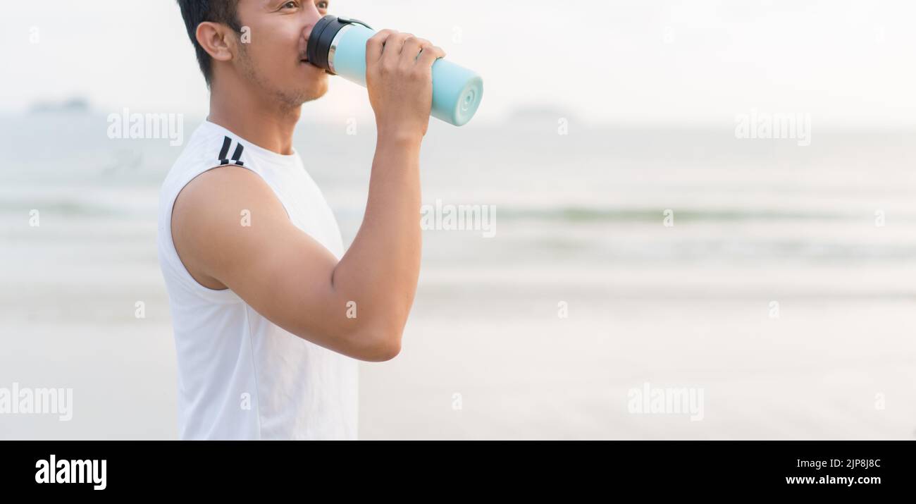 asian sport man drinking water while enjoying a morning run on the ...