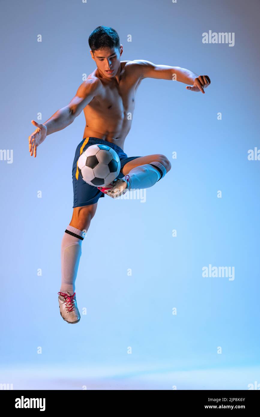 Portrait of young male football player in motion, dribbling, kicking ...