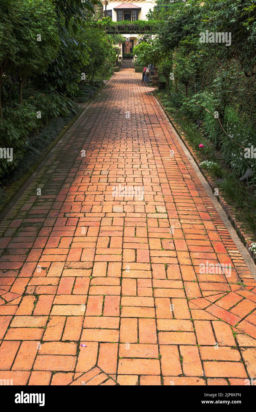A red pavement sidewalk with plants growing on both sides in Garden of ...
