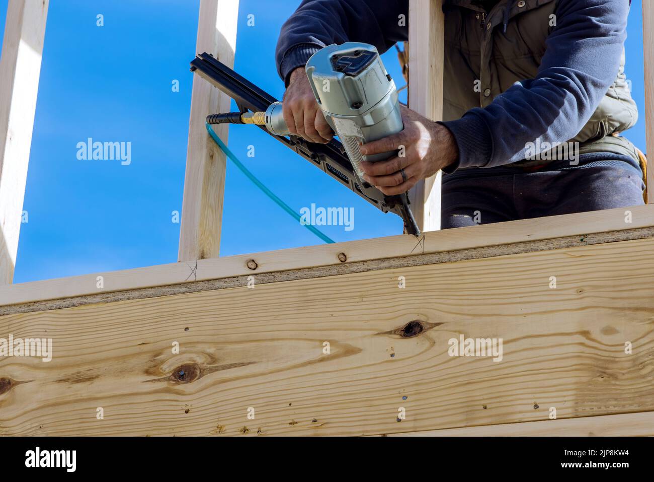 In this case, the builder uses an air hammer when nailing wooden beams ...