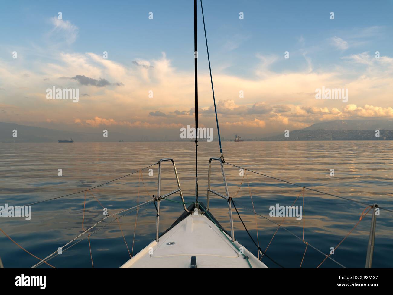 Yacht sailing at the sunset with cloudy sky, nose view. City landscape ...