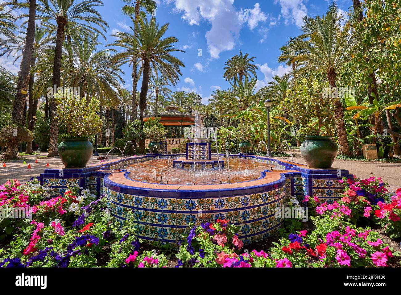 Fountain inside the Palmeral de Elche surrounded by flowers and palm ...