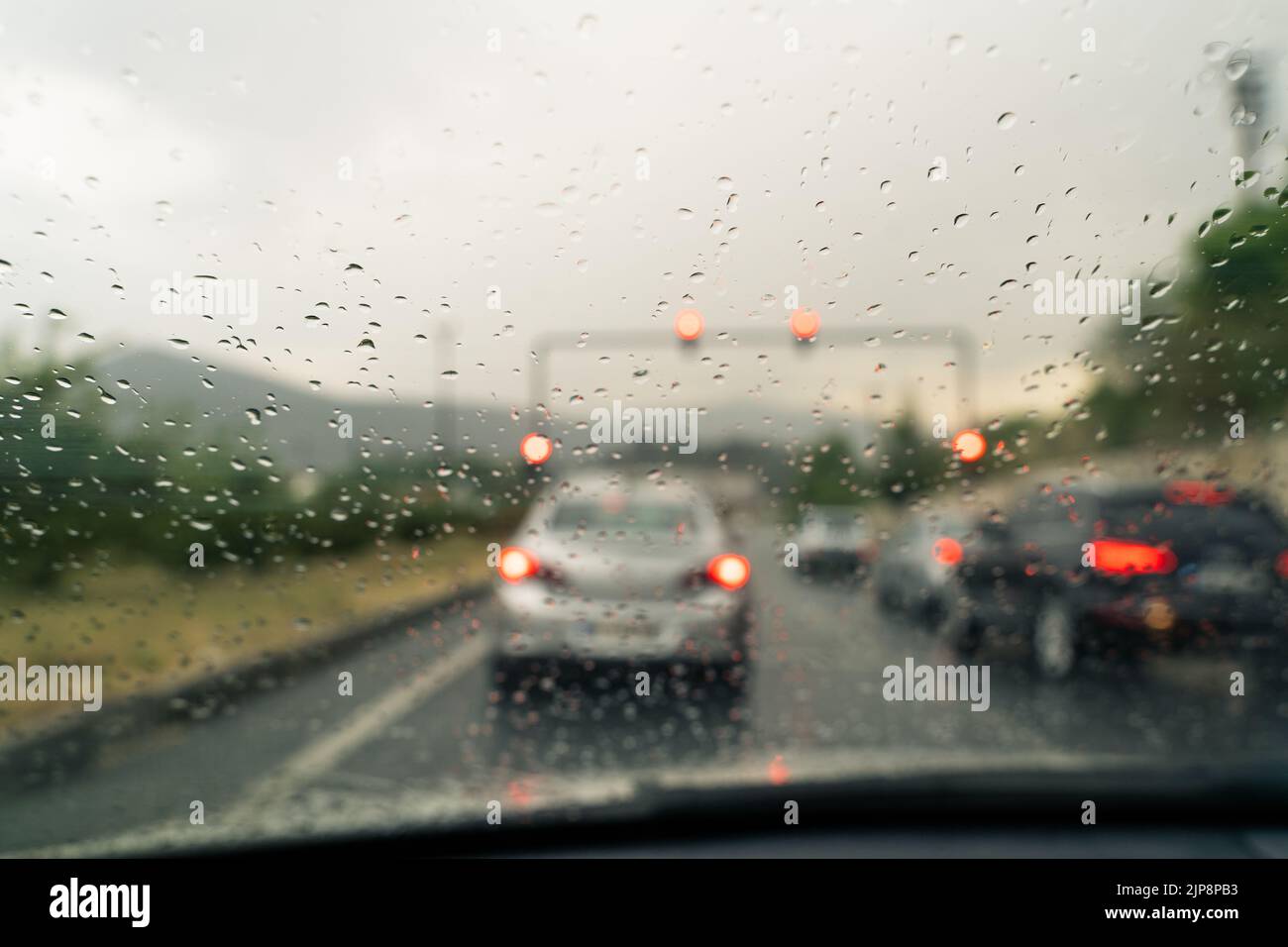 Raindrops on the car window, blurry traffic view at the background ...