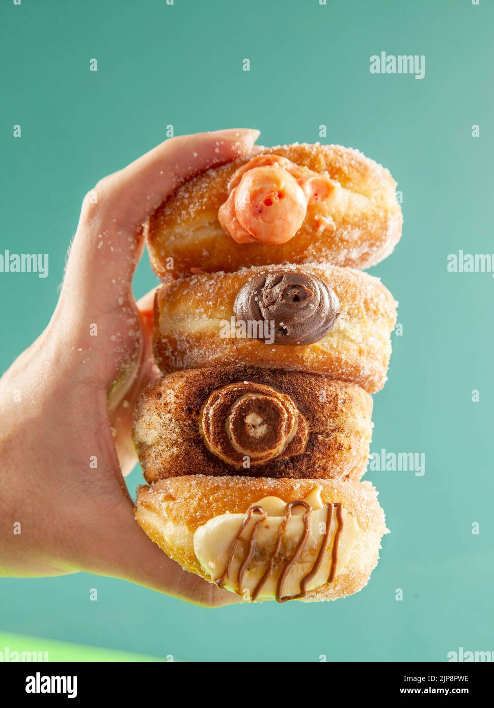 Hand holding stacked four different bombolone doughnuts Stock Photo - Alamy