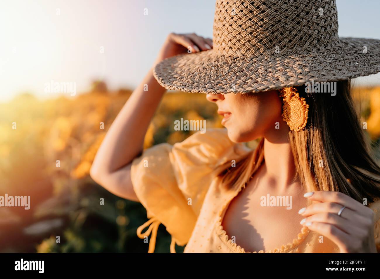 Mysterious stranger woman in straw hat posing on sunflowers background ...