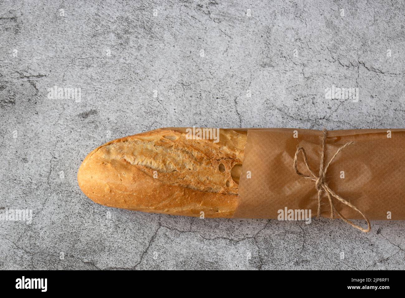 Baguette bread, french stick, wrapped in brown paper tied with string ...