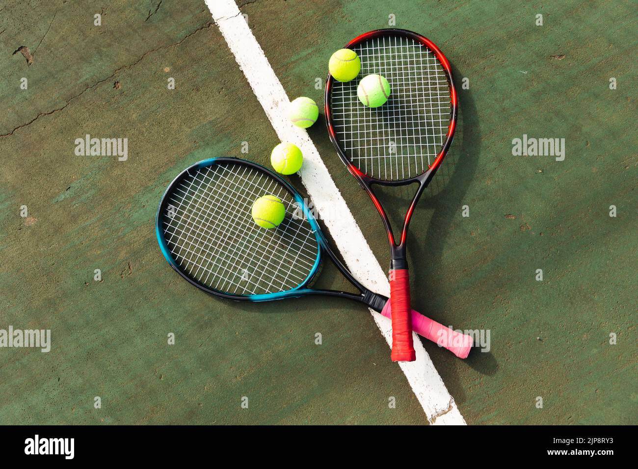 Detail of two tennis rackets and tennis balls lying on the ground at an ...