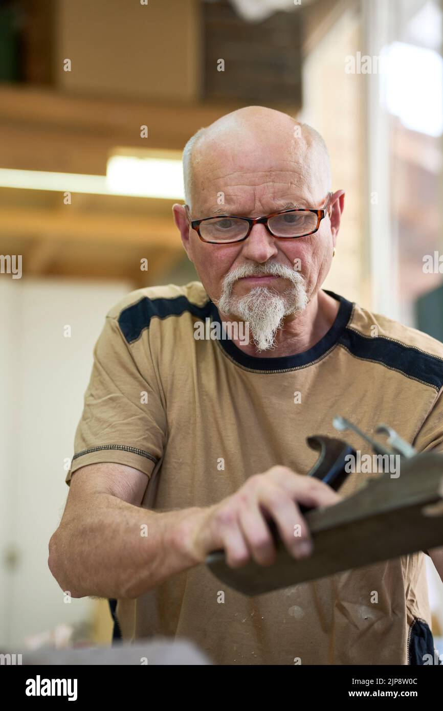 A vertical portrait of a Caucasian carpenter with glasses working in ...