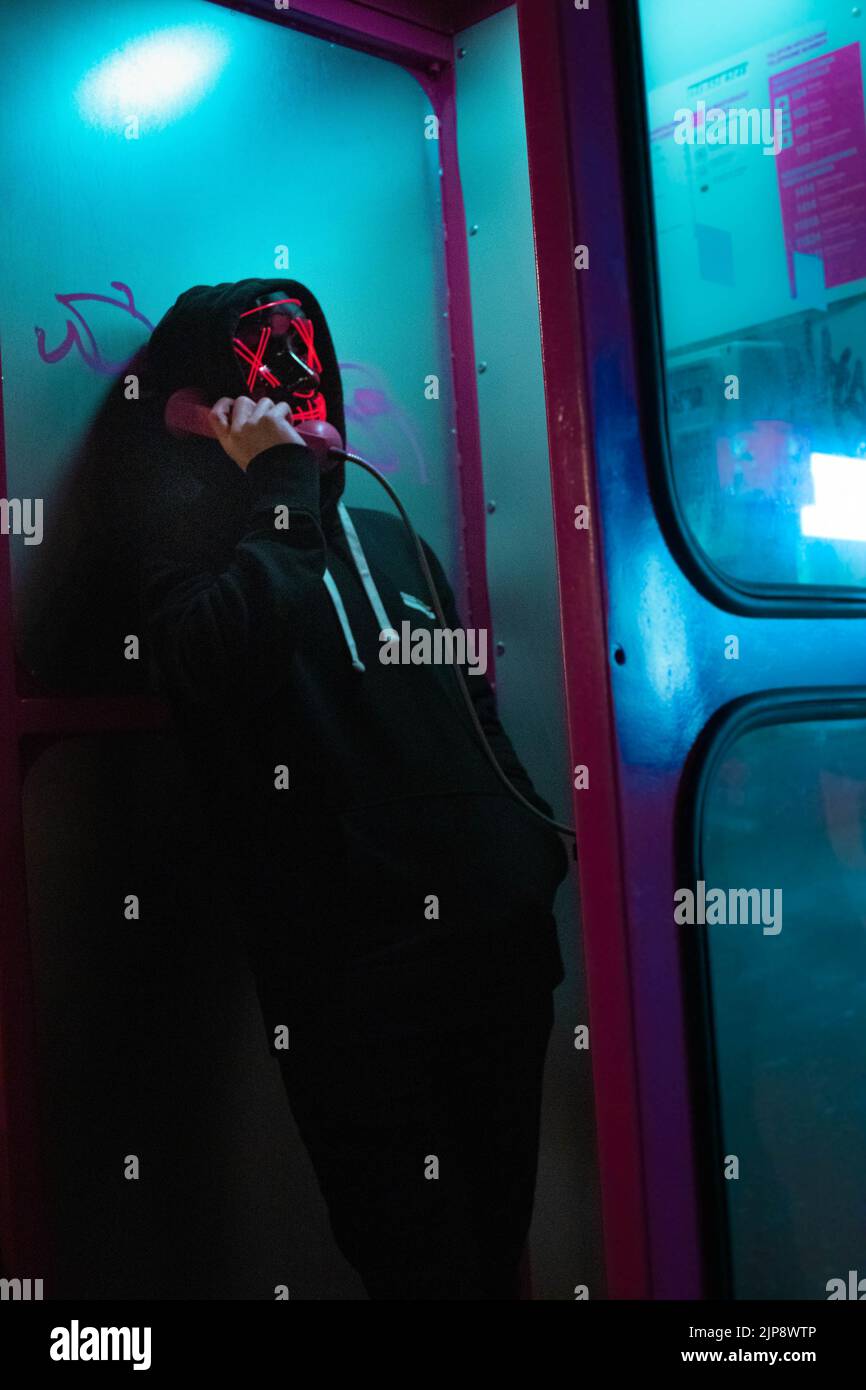 A cool mysterious person in a tech sci-fi mask talking on the old phone ...