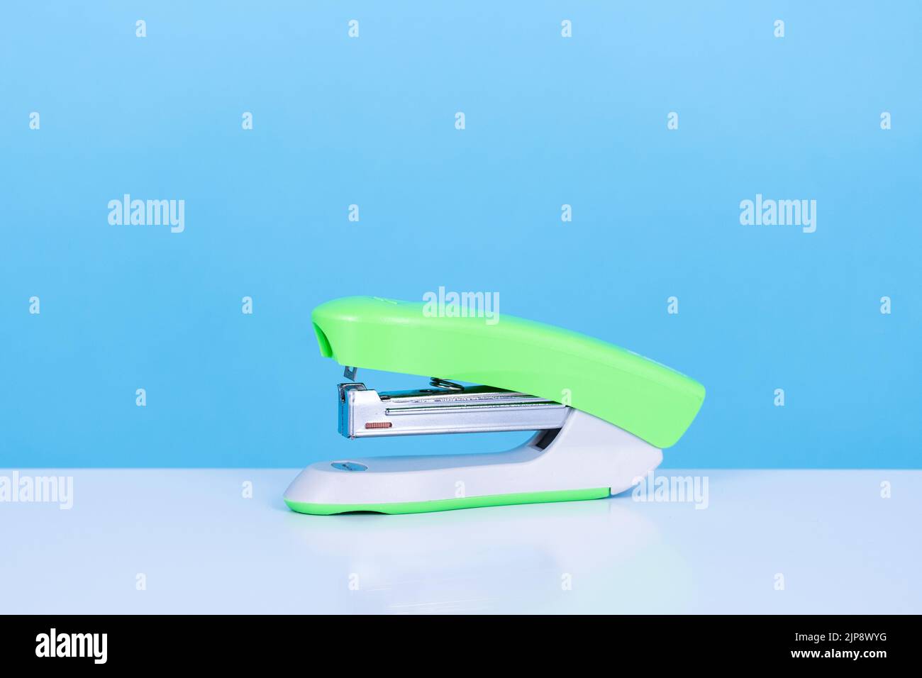 green stapler on desk and blue background. Office supplies Stock Photo ...