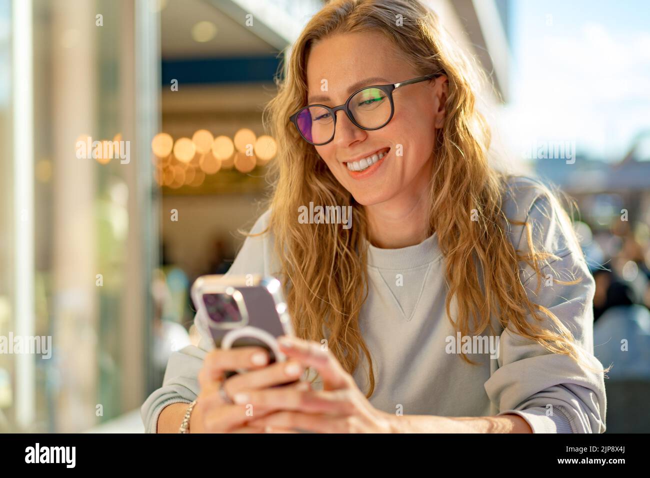 Young woman in a cafe reading a text message from her mobile phone ...