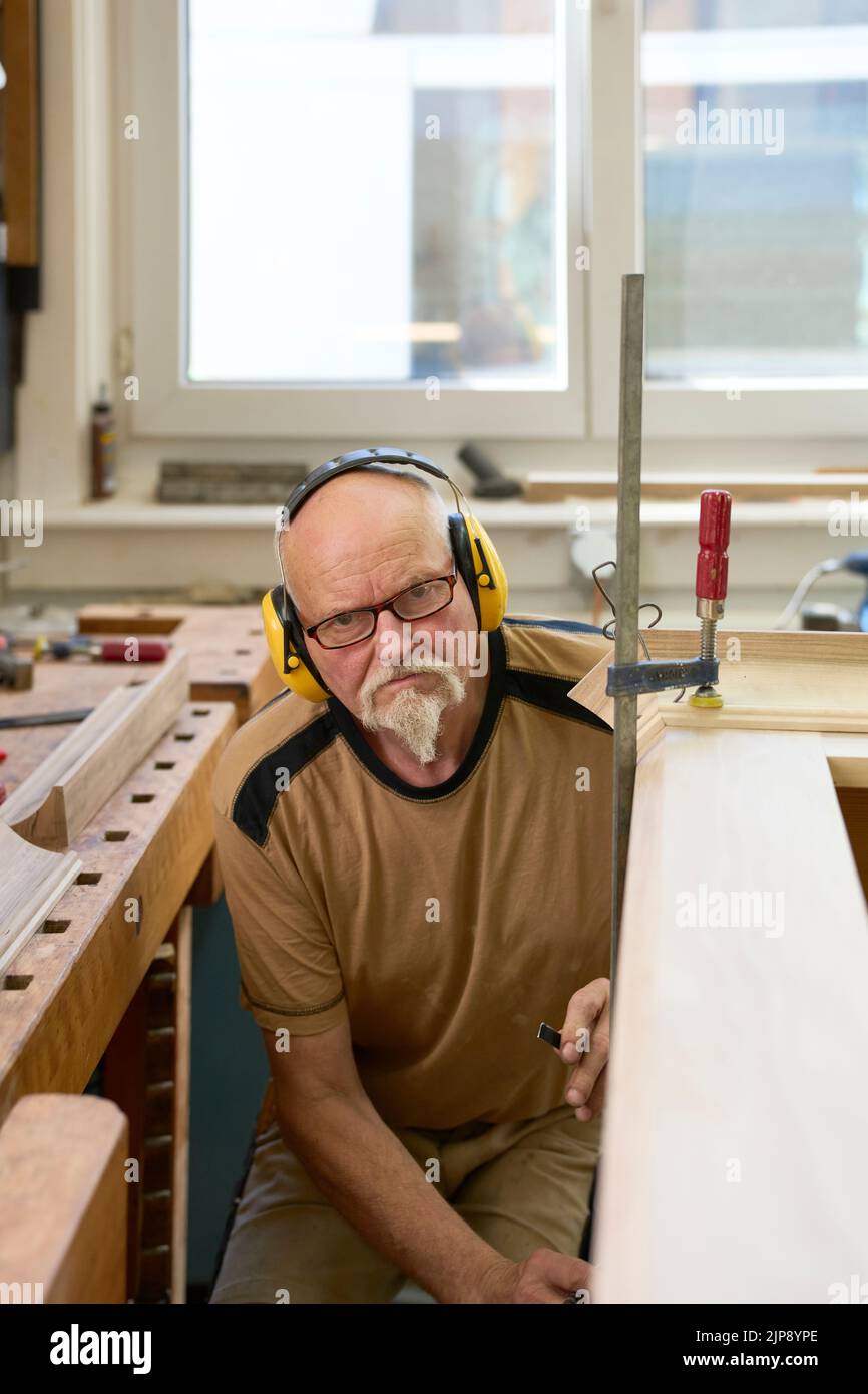 A vertical shot of a male Caucasian carpenter taking measurements in ...