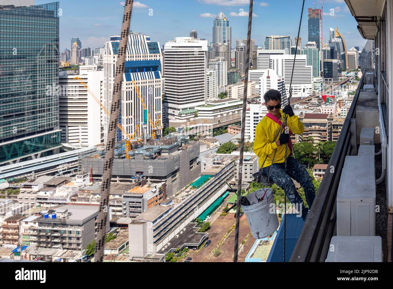 Thai worker using Bosun Chair to repair skyscraper, abseiling above ...