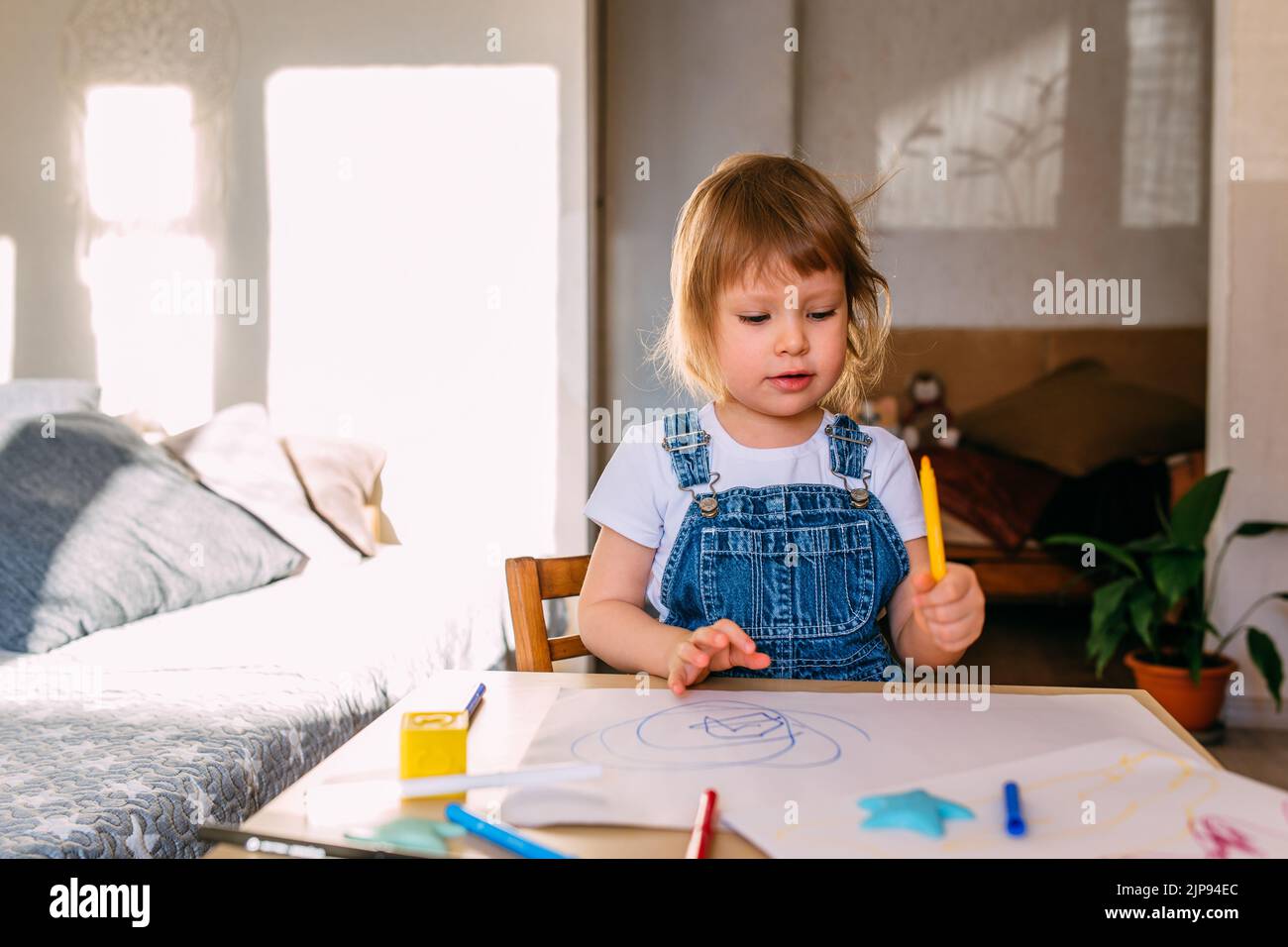 Small child at home at the children's table draws with felt-tip pens ...