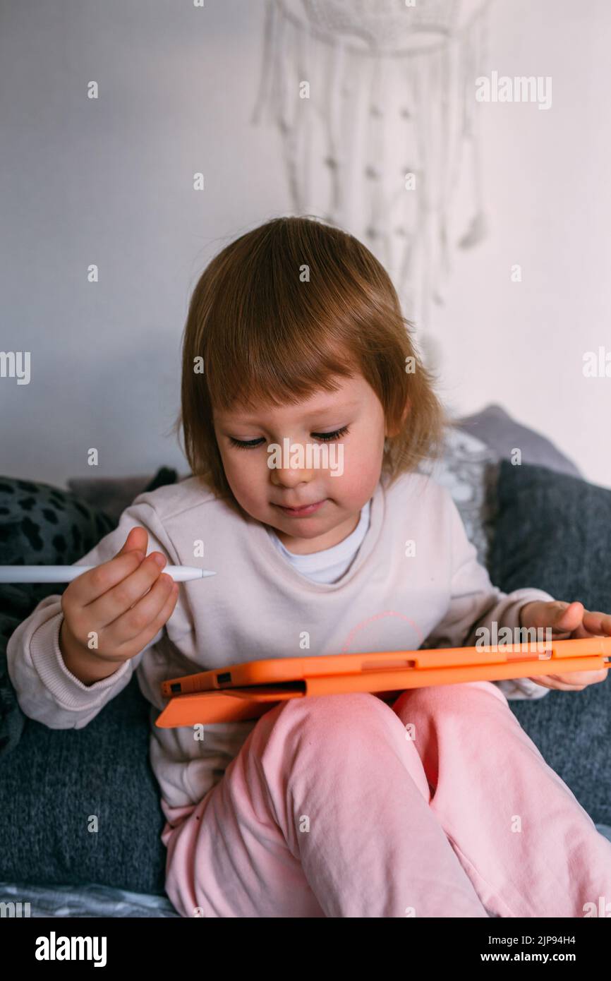 Child using technology. Toddler at home with a tablet and a pen stylus ...