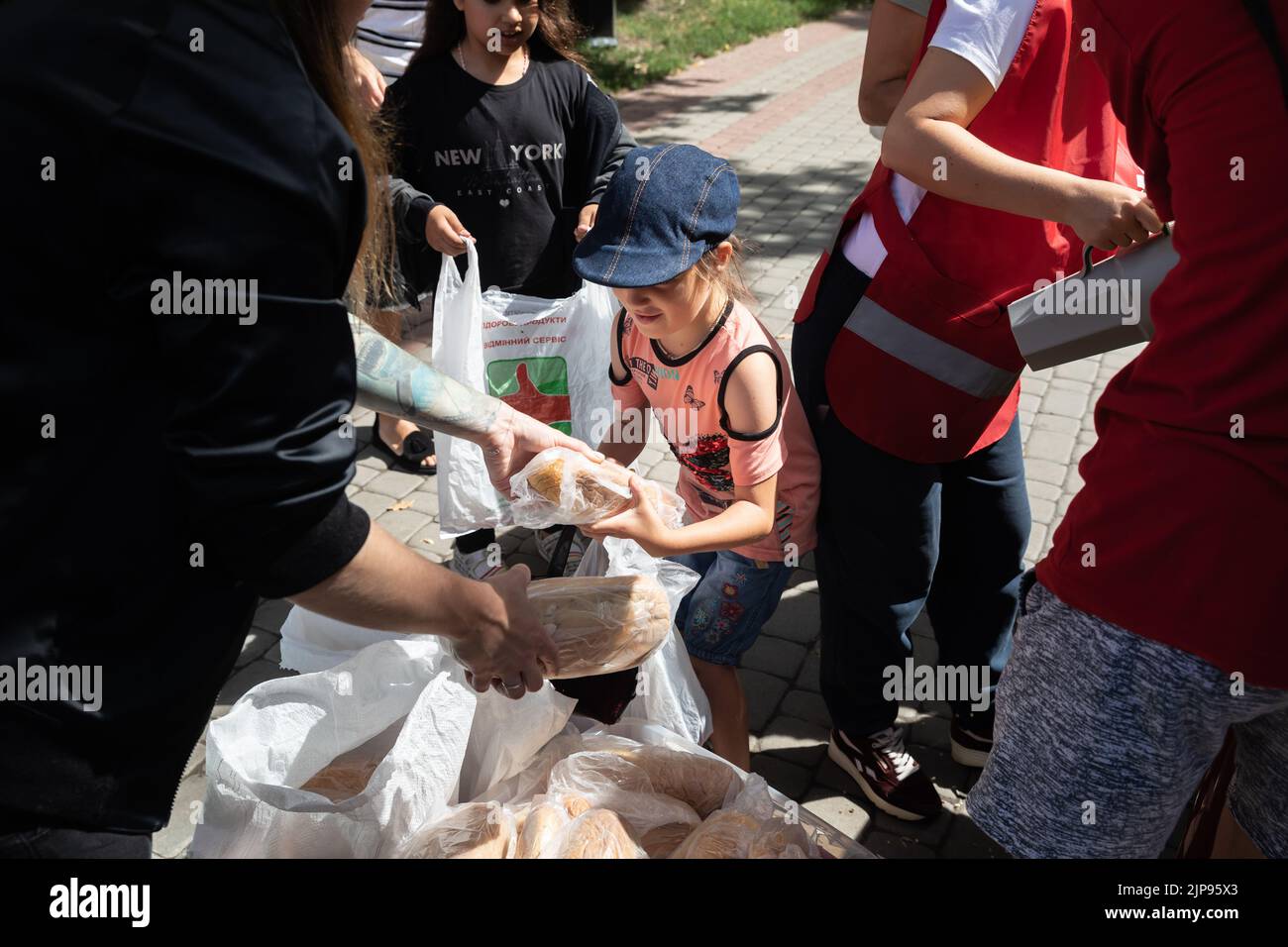 KHARKIV, UKRAINE - Aug. 02, 2022: Volunteer girl gives a loaf of bread ...