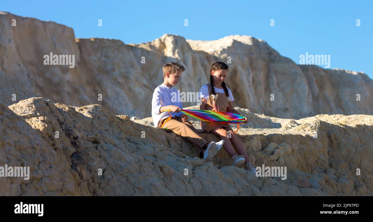 Brother and sister watching a kite sitting on a mountain Stock Photo ...