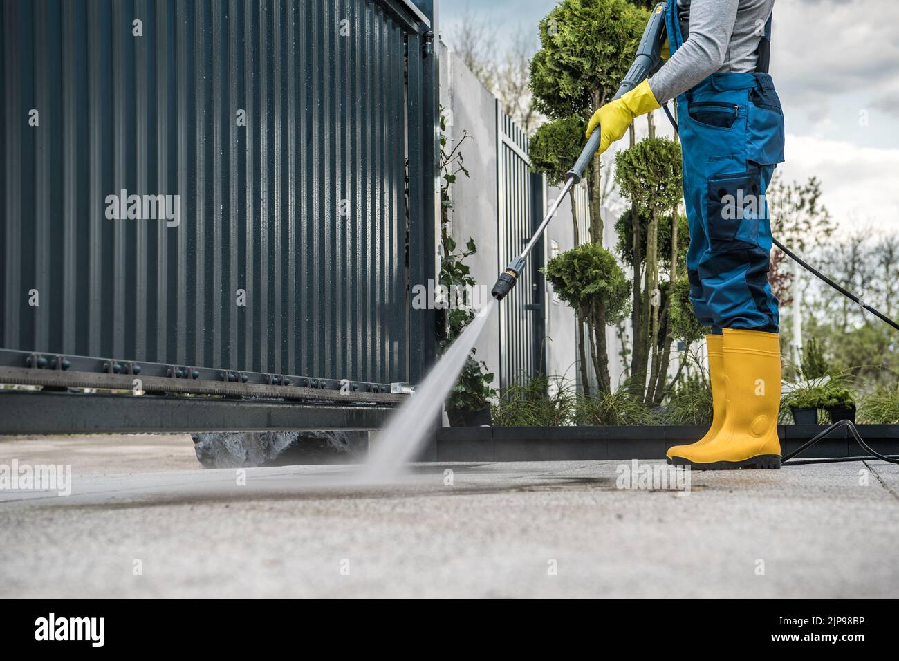 Worker Wearing Protective Uniform and Yellow Rubber Boots Cleaning the ...