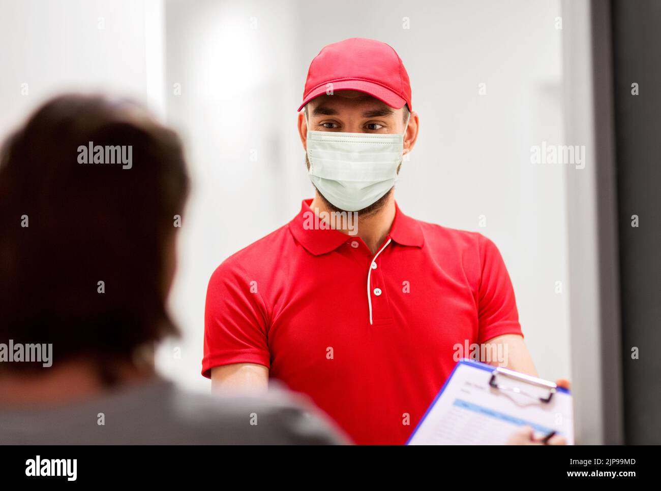 delivery man in mask and customer signing papers Stock Photo - Alamy