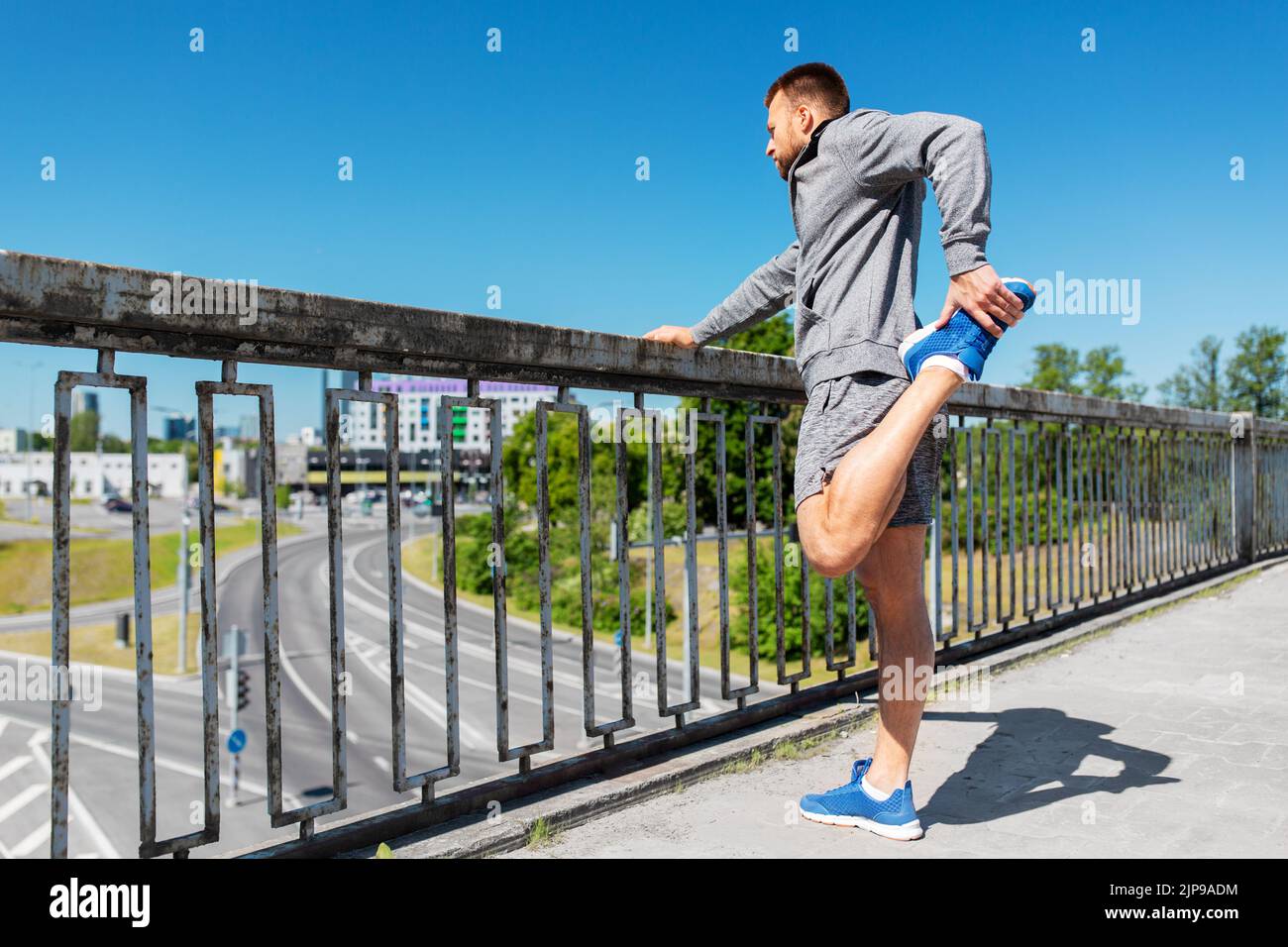 man stretching leg on bridge Stock Photo - Alamy