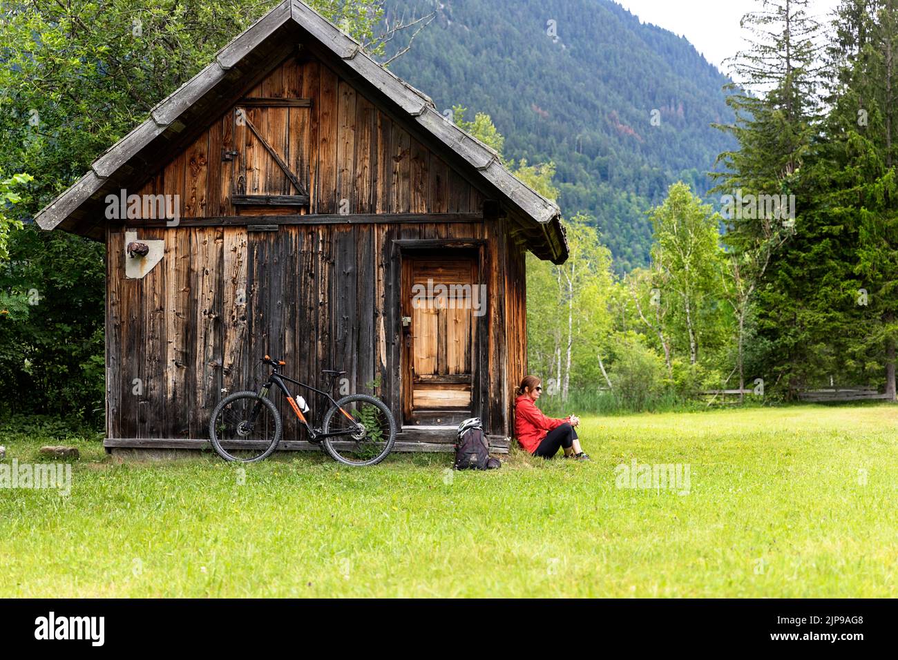 Woman cyclists relaxing at the traditional wooden cottage after bicycle ...