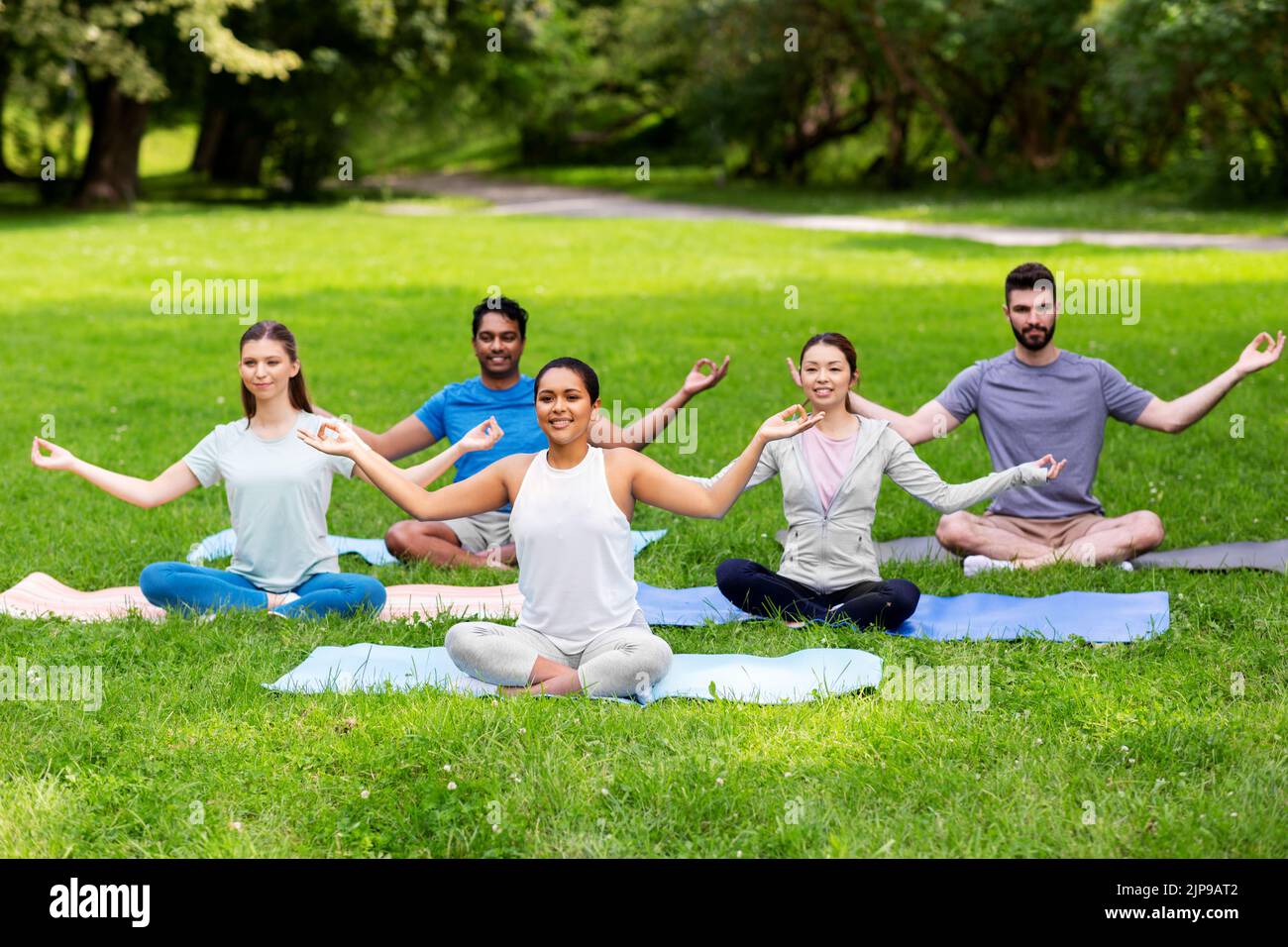 group of happy people doing yoga at summer park Stock Photo - Alamy
