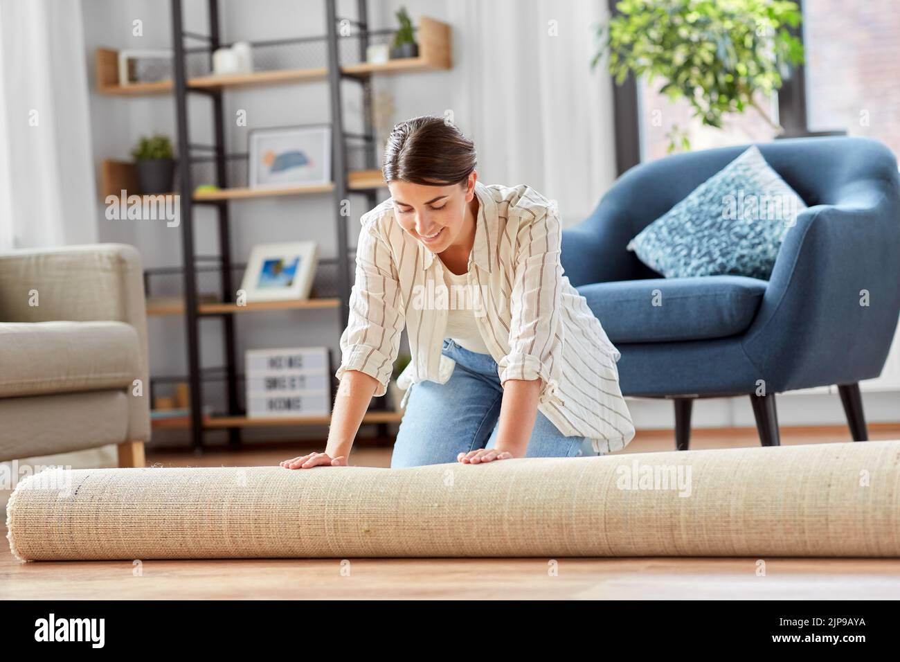 young woman unfolding carpet at home Stock Photo - Alamy