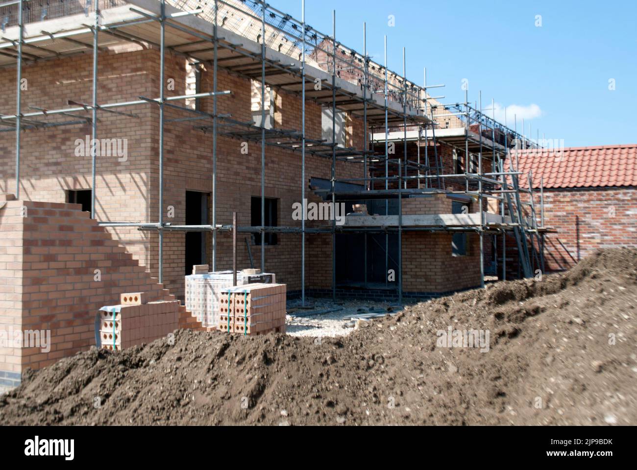 Large pile of earth in front of a partially constructed house with ...