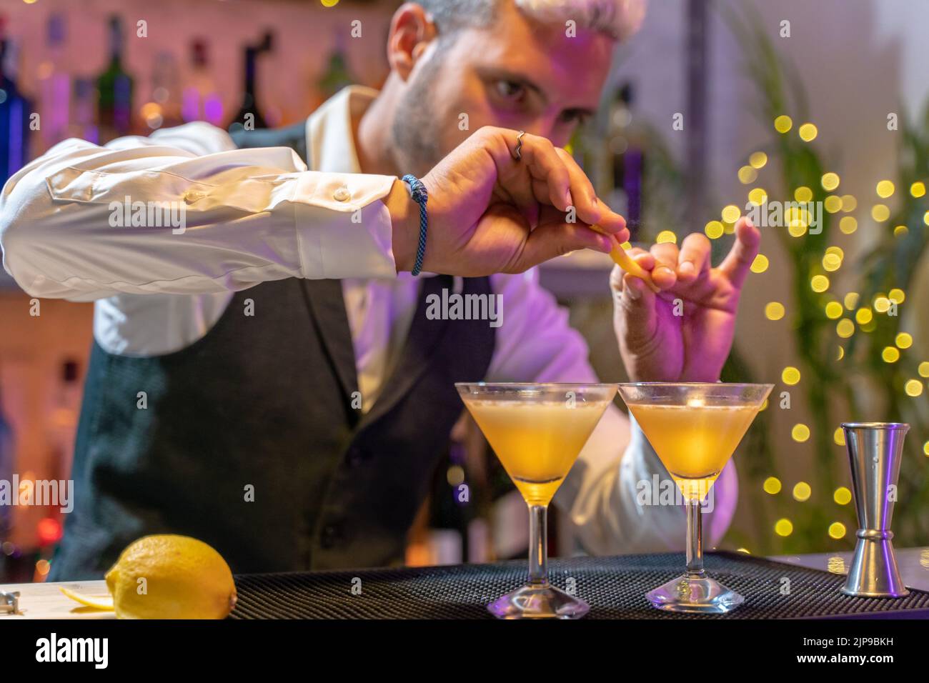Handsome young barman making elegant cocktail in night club on bar ...