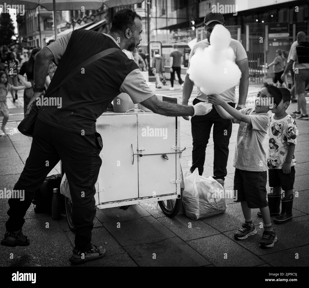 A grayscale shot of an excited young boy receiving a stick of cotton ...