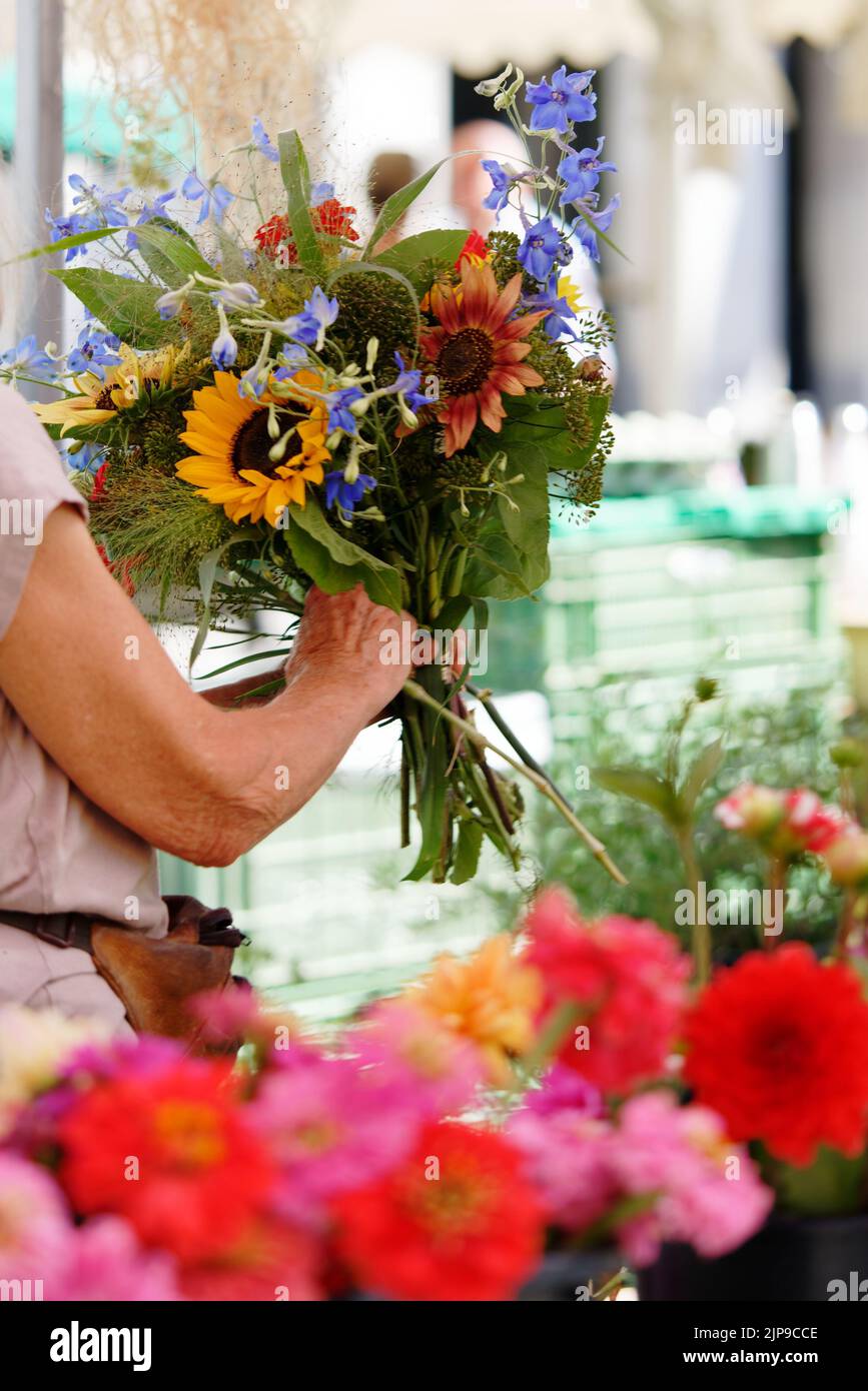 A closeup of a woman selling a beautiful bouquet of different homegrown ...