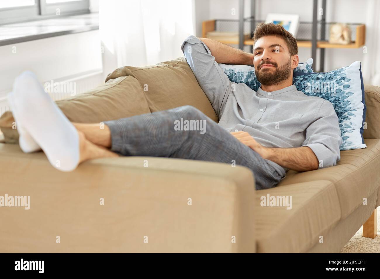 young man sitting on sofa at home Stock Photo - Alamy