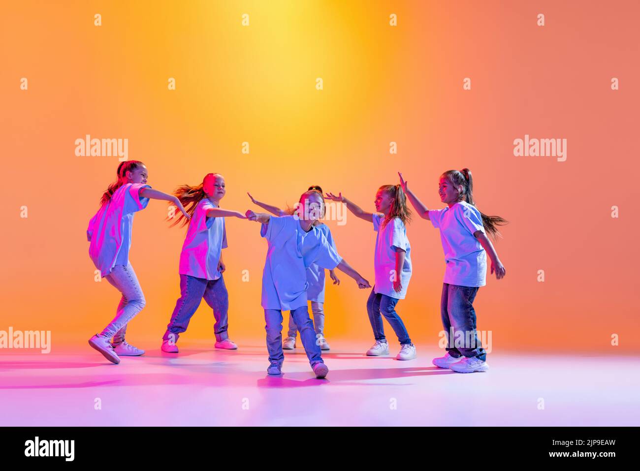 Dance group of happy, active little girls in t-shirts and jeans in ...